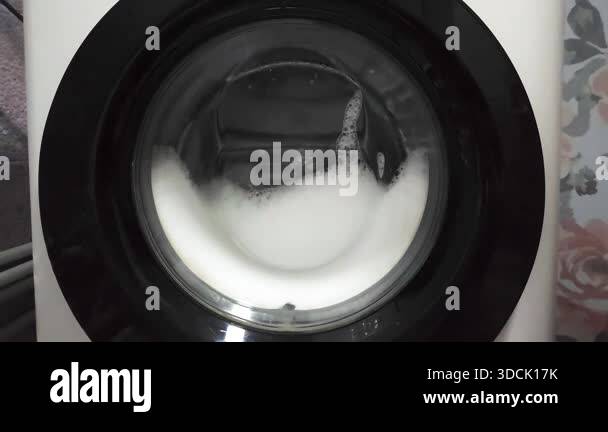 white soapy detergent foam spinning inside washing machine, slow motion ...