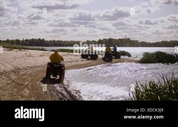 Group quad ride along sandy coast under cloudy sky, convoy of riders in ...
