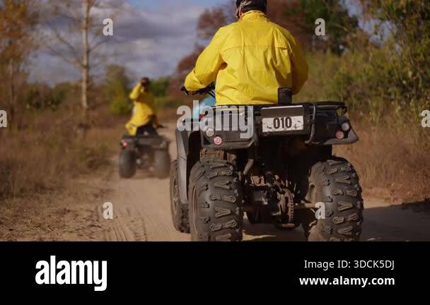 Slow motion. Rear view two atvs on trail close tandem ride with riders ...