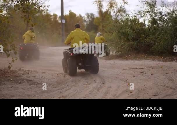 Four riders on AVTs kicking dust through sandy forest trail, yellow ...