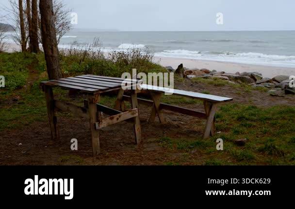 Rustic wooden picnic table and benches set on grassy terrain near ...