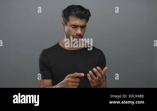 Man points finger to finger in grey studio under dramatic lighting with ...
