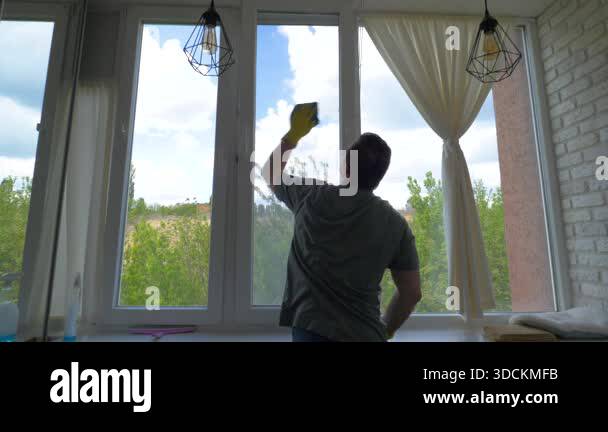 Housekeeping cleaner washes a window in a house with a rag, splashes ...