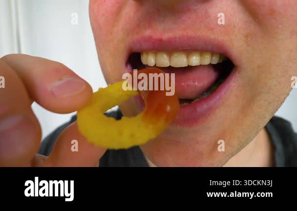 Man Eating potato chips rings with ketchup. Eating corn snacks with ...