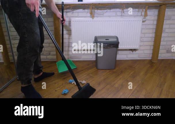 Sweep dirt into dustpan and throw trash into trash bin. Man cleans dirt ...