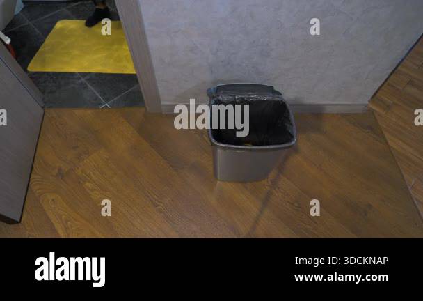 A man in an apartment throws trash into a trash can, throwing crumpled ...