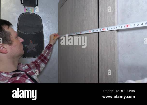 A master handyman measures a door with a tape measure and a ...