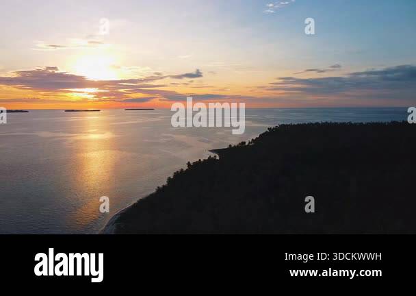 Sideways drone flight during sunset with Sikandang Island forming a ...
