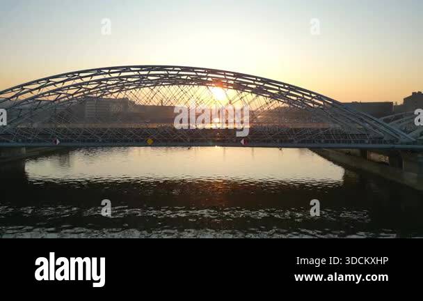 Bridge structure illuminated by sunset reflections over water ...