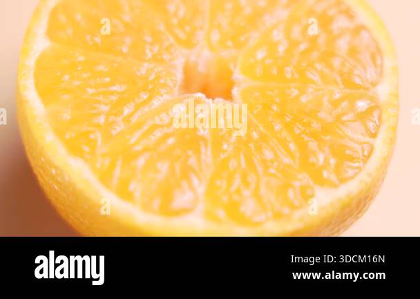 Macro view of a mandarin half rotates, revealing bright segments and ...