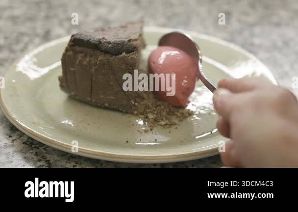 Chef plating a dessert by adding a smooth scoop of ice cream beside a ...