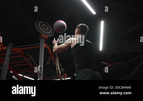 Athlete throwing fitness ball at gym. Fit man do ball workout in ...