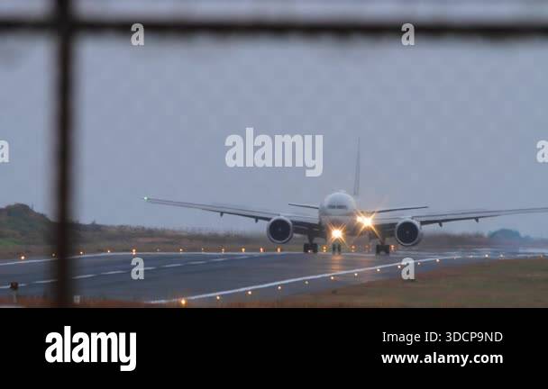 Widebody airliner landing at dusk, illuminated by soft evening light ...