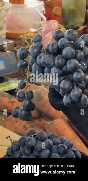 Male hand choosing grapes in the supermarket, putting to the basket ...