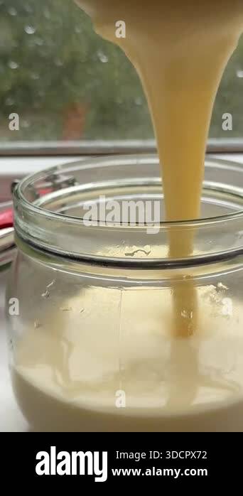 Processed cheese preparation pour into a glass jar, liquid consistency ...
