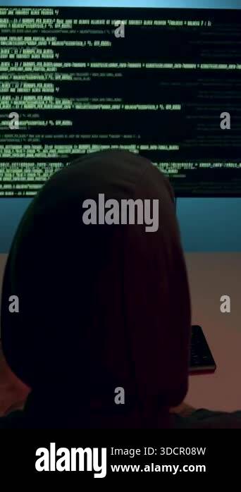 Hooded individual immersed in a cyber attack, operating multiple ...