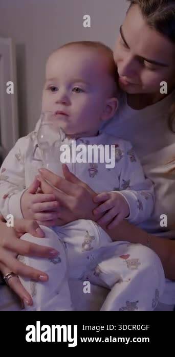 A mother lovingly assists her infant with a nebulizer in a warm ...