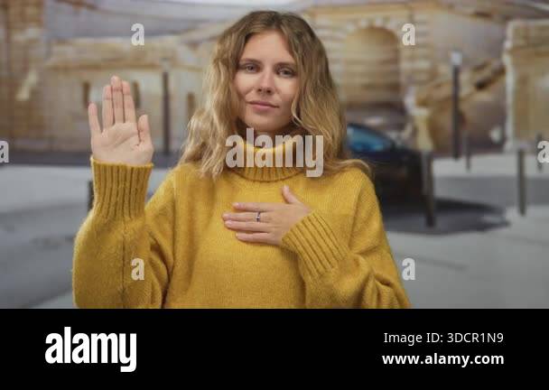 Woman lifts hand in a swearing street portrait, her blonde young ...