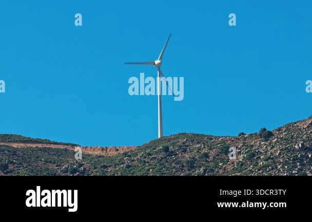 Close up view of wind turbine on rocky mountain slope against clear ...