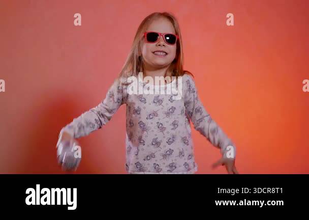 Young funny girl in pajamas in red sunglasses holds a silver microphone ...
