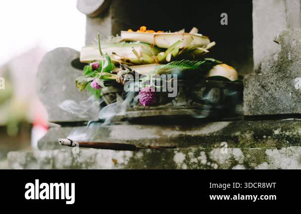 Canang Sari offering placed on a traditional Balinese stone shrine with ...