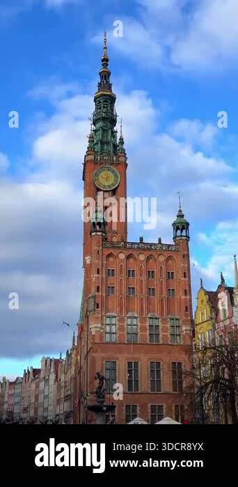 A clock tower is visible in Gdansk with colored buildings nearby. Birds ...