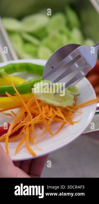 Employee builds a colorful salad at vegetable station in restaurant ...