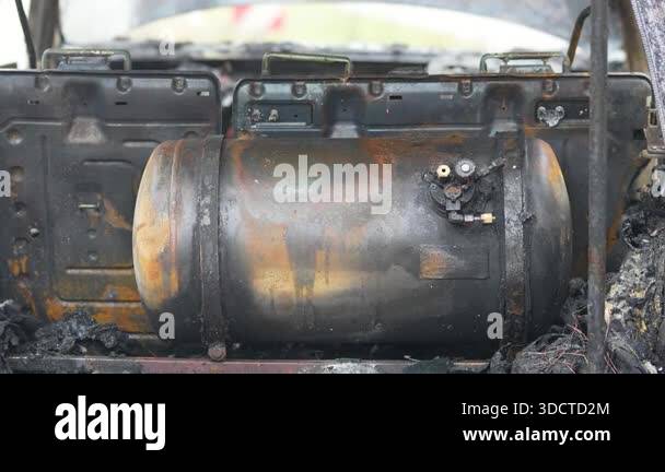 A close-up view of a gas tank reveals the effects of fire damage, with ...