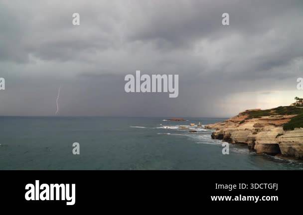 Lightning bolt over stormy sea with heavy dark clouds and waves near ...