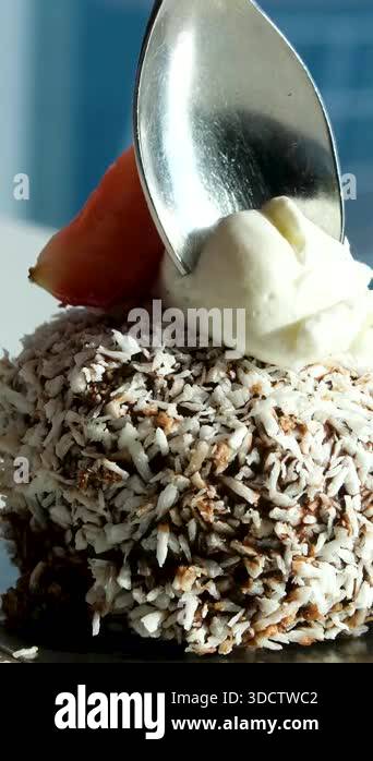 Hand uses spoon to scoop chocolate cake topped with cream and ...
