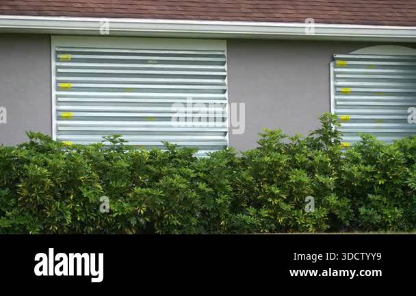 Boarded up windows with steel storm shutters for hurricane protection ...