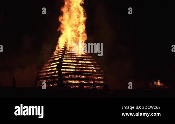 Slow-motion of a large wooden bonfire burning intensely, with tall ...
