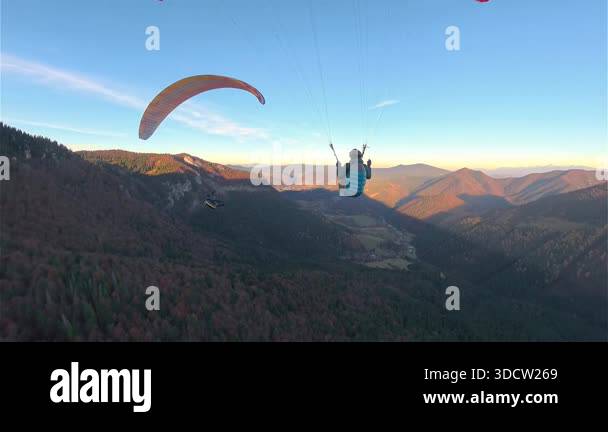 Two paragliders soar calmly above a autumn forest, captured with a ...