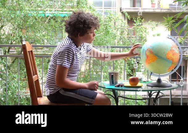 boy taking morning breakfast on home balcony watching and playing with ...