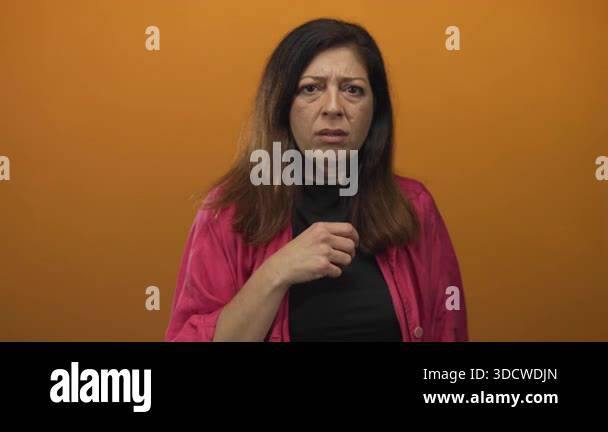 Middle aged hispanic woman wearing pink jacket with hand on chest and ...
