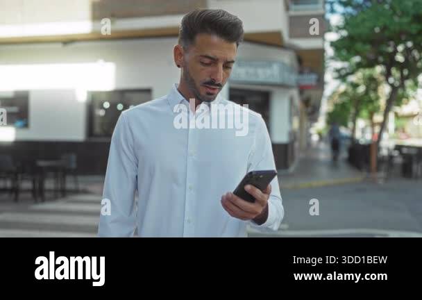 Man in white shirt holds smartphone in hand on busy city street ...