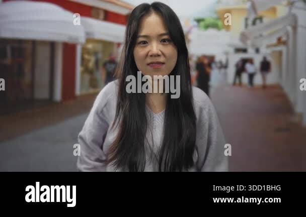 Chinese woman making watchful hand gesture on busy street in outdoor ...