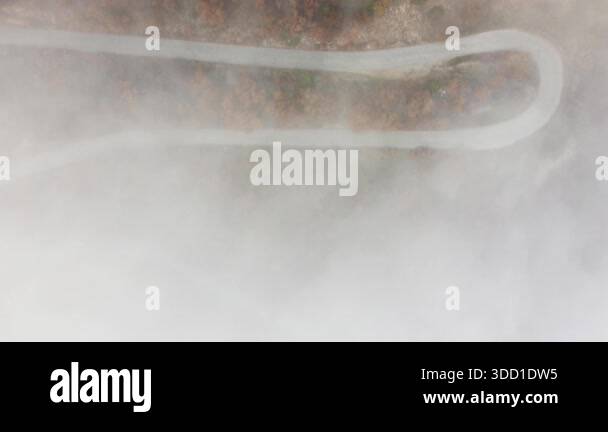 Aerial view of a winding mountain road through thick fog. The road ...