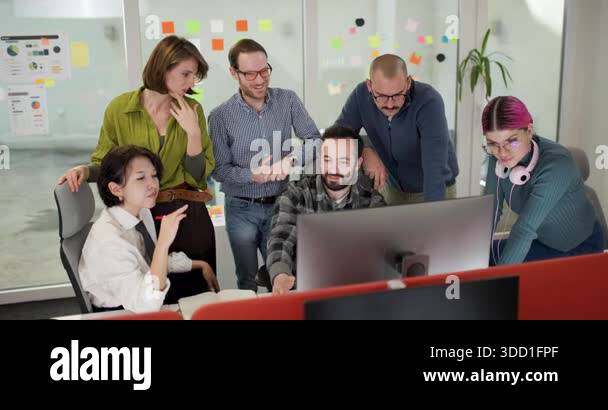A group of business professionals gathers in an office. They look at a ...