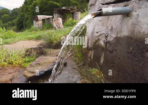 A river source tap emerges from a rocky surface, releasing fresh water ...