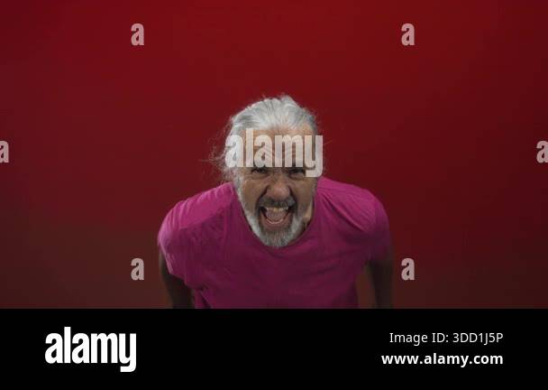Man with hoary long hair and beard, magenta shirt, fists raised and ...