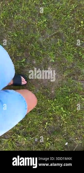 Foot in black sandals steps on grass, highlighting the texture of the ...