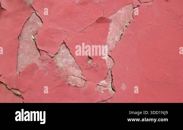 A close look at a cracked red wall in a city showing signs of wear ...