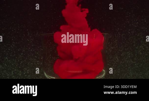 Red splash. Filling glass. Defocused vibrant color ink wave water ...