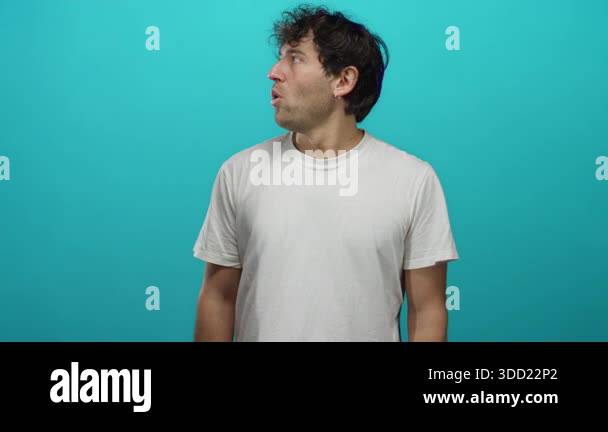 Hispanic man points aside surprised against blue background, wearing a ...