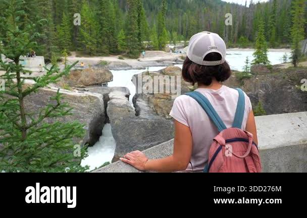 Female tourist with backpack admiring the natural bridge rock formation ...