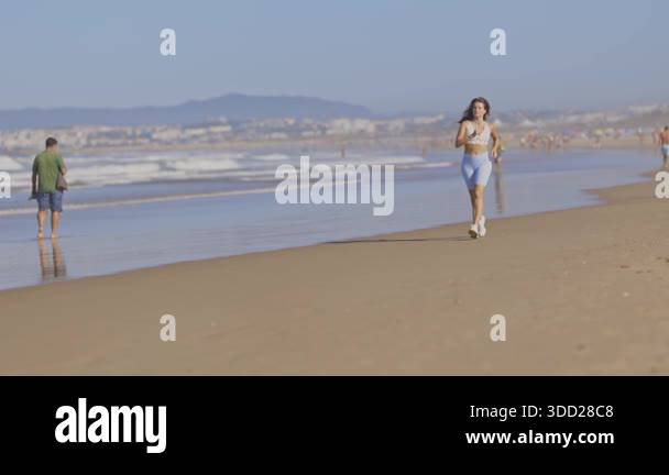 Fit young woman running on the beach during her morning cardio workout ...