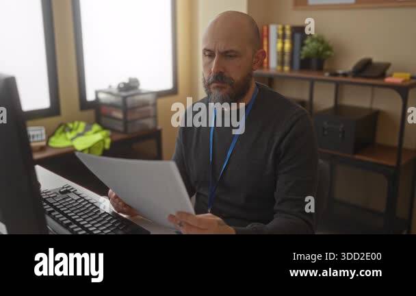 Man with beard reviewing documents at desk in modern office featuring ...