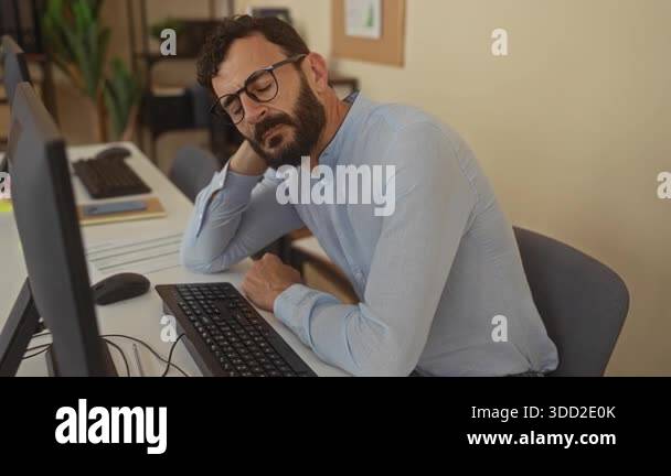 Hispanic man with beard, tired and resting head on hand at office desk ...