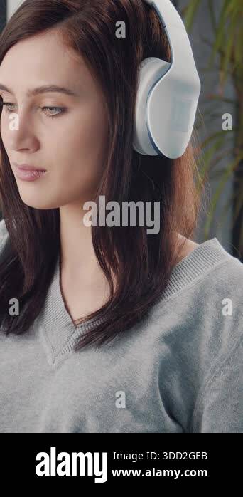 Woman enjoys music with headphones while smiling in a vertical frame ...